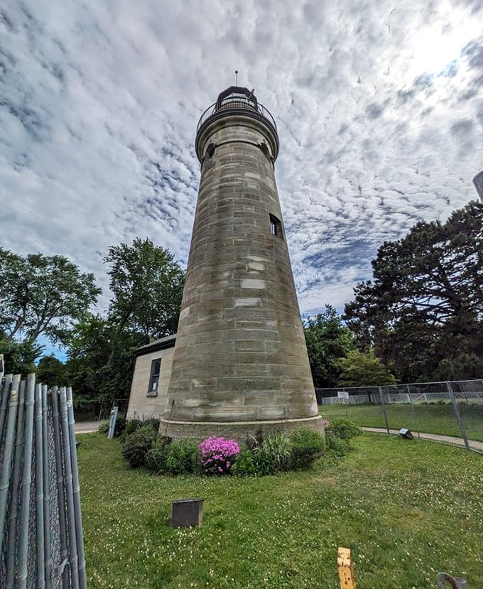 The iron fence surrounding the lighthouse isn't just for protection—it's framing a perfect picture that belongs on your holiday card.