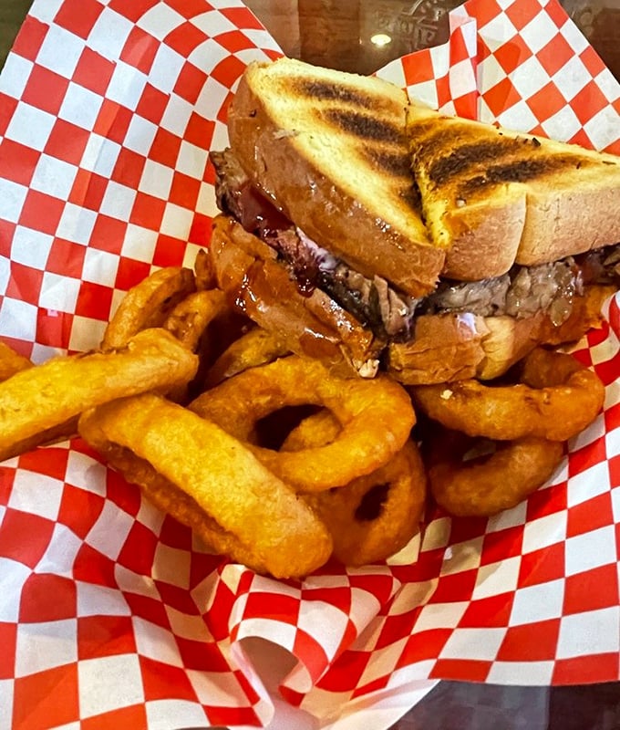This sandwich isn't just lunch—it's an event. Toasted bread barely contains the pulled pork while onion rings stand by as worthy companions.