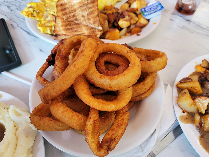 Onion rings stacked higher than your weekend plans—golden, crispy hoops of happiness that make sharing feel like a personal sacrifice.