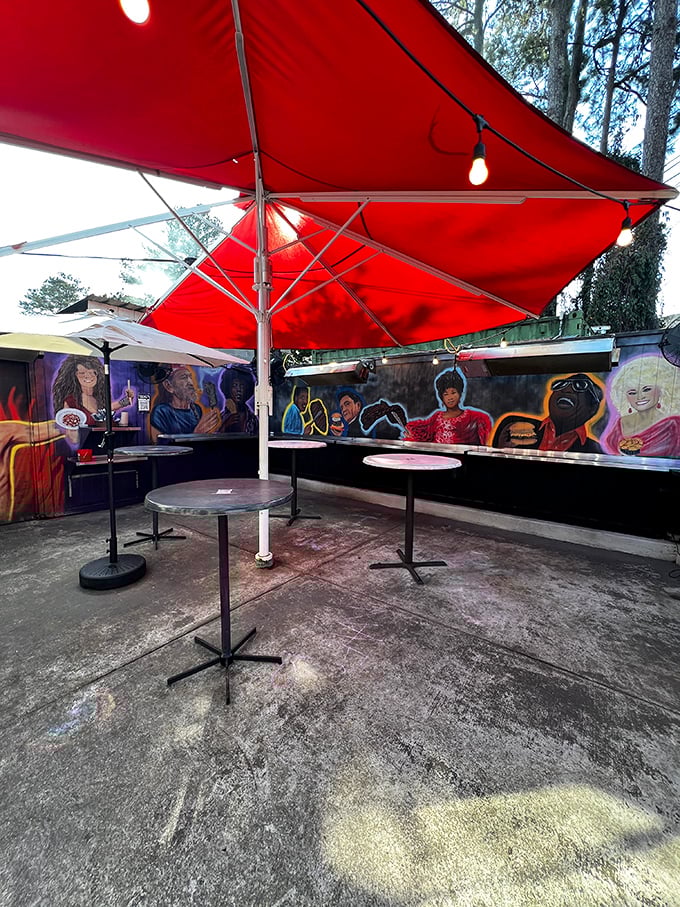 The outdoor seating area – where red umbrellas provide shade and colorful murals celebrate the cultural diversity that inspires the menu.