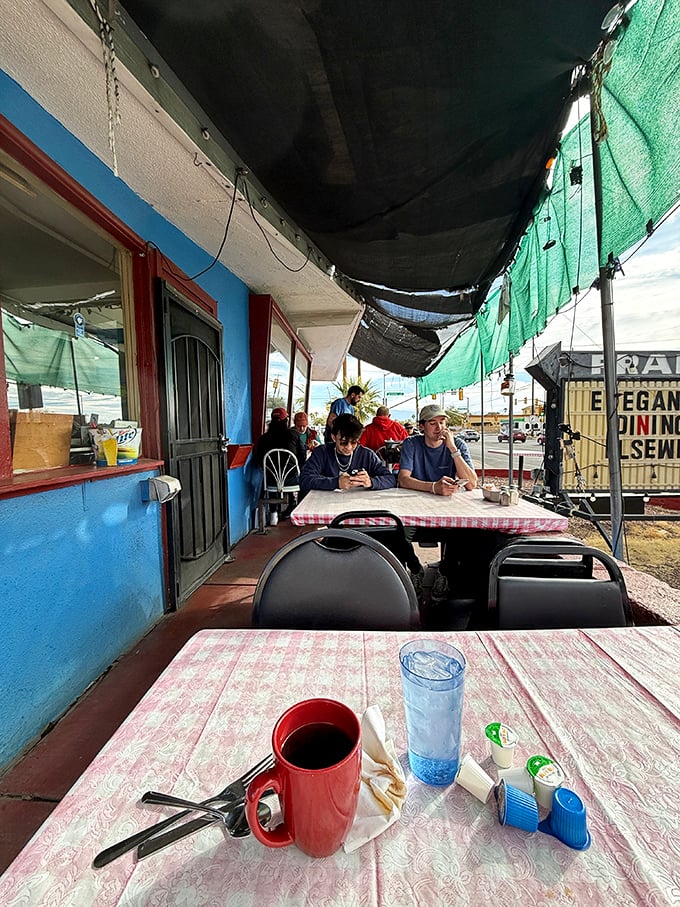 The outdoor seating area offers fresh air with your fresh coffee – red mugs and checkered tablecloths create that classic diner vibe.