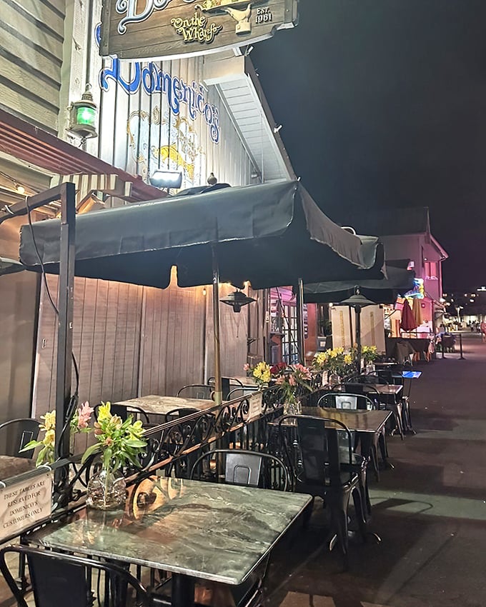 Evening transforms the outdoor seating into a romantic escape – string lights twinkling above as the harbor's nighttime symphony plays on.