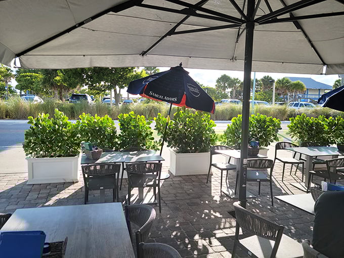 The outdoor patio—where umbrellas provide shade, sea breezes provide ambiance, and nobody's checking their watch because island time is the only time that matters.