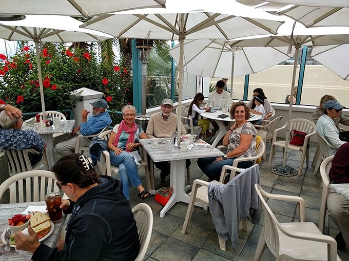 The outdoor patio—where umbrellas create islands of shade and ocean breezes deliver complimentary seasoning to every table.