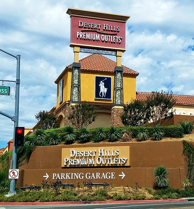 The entrance sign stands like a retail lighthouse, guiding shoppers safely to harbor while warning their credit cards of impending doom.