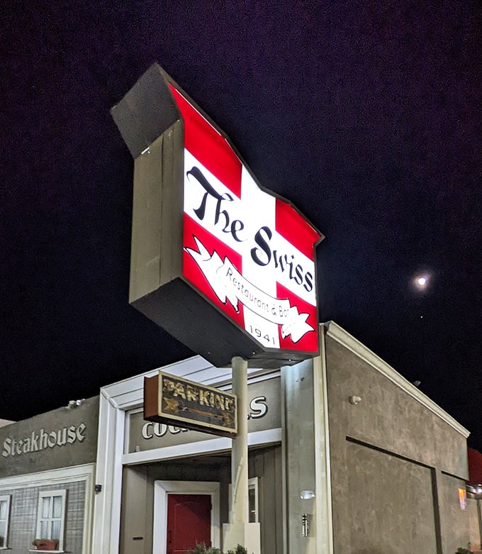 The Swiss Restaurant sign glowing against the night sky—a beacon for hungry travelers and locals alike.