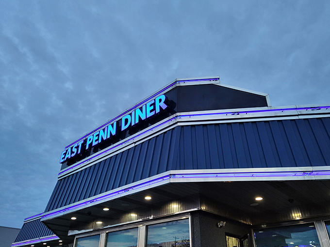 As evening approaches, the East Penn Diner sign glows with neon promise against the twilight sky—a blue-lit beacon for hungry travelers.