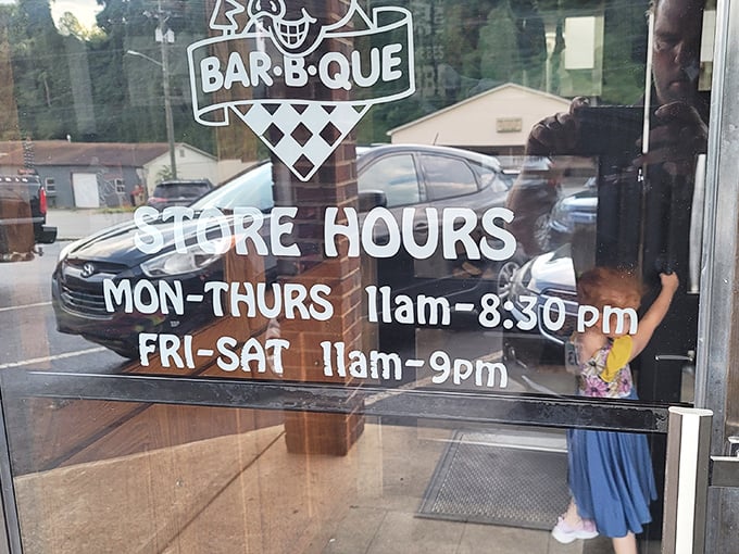 Store hours painted on glass – the most important information for barbecue pilgrims. Note the extended weekend hours for serious smoked meat devotion. 