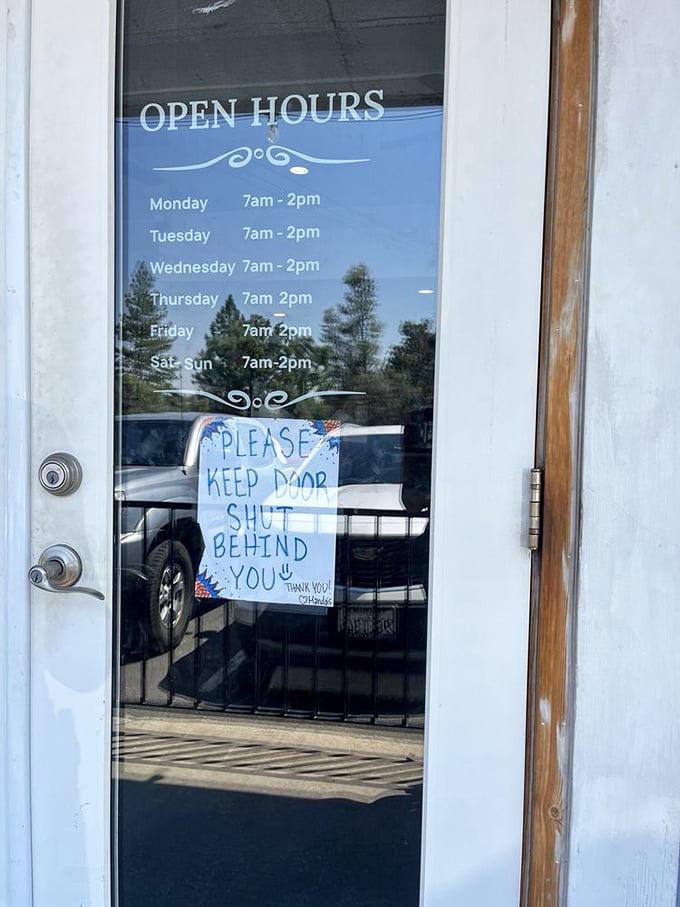 Hours posted with a handwritten reminder to keep the door shut—small-town charm that's worth setting your alarm for.