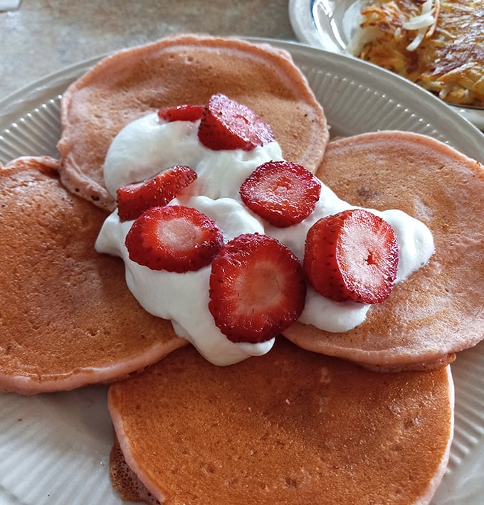 Strawberry pancakes that make you question why anyone would ever choose cereal. That whipped cream isn't just a topping—it's a necessity.