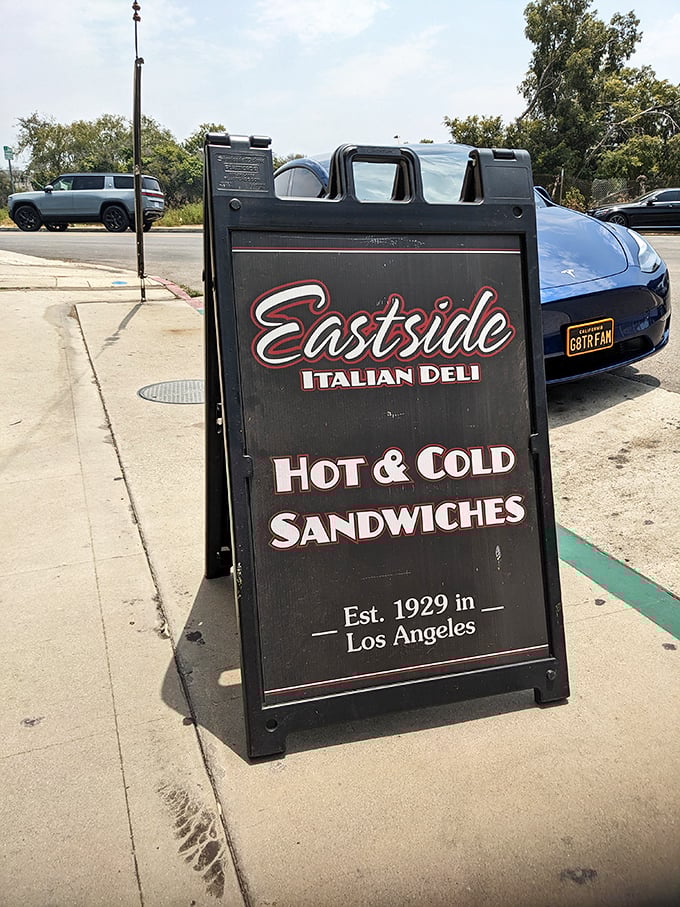 The sidewalk sign stands like a sentry, guiding hungry pilgrims to sandwich salvation since 1929 – some traditions are worth preserving.