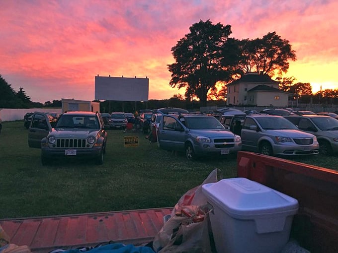 Nature provides the most spectacular opening act—a fiery sunset that silhouettes the screen and transforms ordinary cars into magical viewing pods.