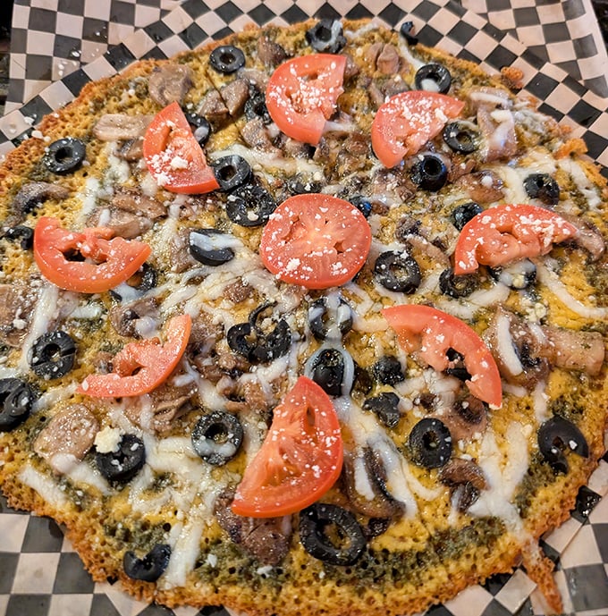 Pizza perfection with a twist – fresh tomatoes and black olives atop a golden cheese canvas that makes traditional crust seem unnecessary.