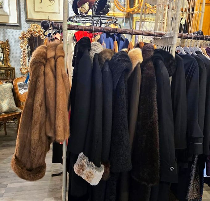 Vintage fur and wool coats hang like sleeping sentinels of fashion history, waiting for winter or perhaps a Gatsby-themed party to make their comeback.