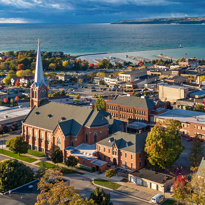 This bird's-eye view reveals Petoskey's perfect positioning: historic architecture nestled between rolling hills and sparkling bay waters.