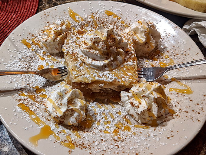Apple strudel crowned with whipped cream and caramel drizzle—the kind of dessert that makes you consider ordering a second before finishing the first.