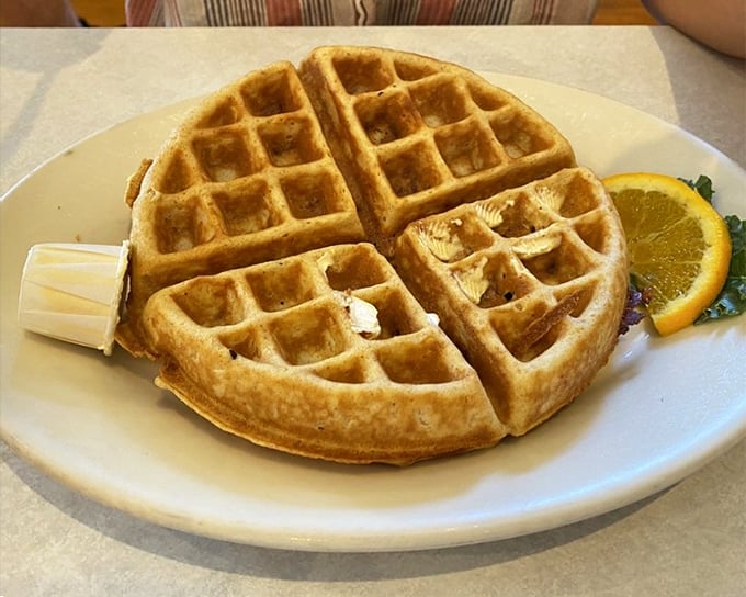 This golden waffle with its perfect grid of syrup-catching squares stands ready for butter's melting embrace—breakfast architecture at its finest.
