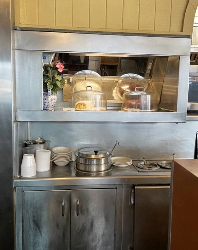 Behind the scenes, the kitchen pass-through offers glimpses of baked goods waiting patiently under glass domes—edible treasures guarded until the perfect moment.