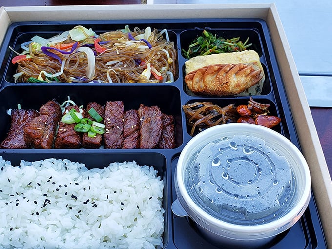 The bento box presentation proves that Korean BBQ travels well—bringing that tabletop grill experience to your home, office, or secret eating spot.