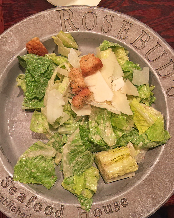 A Caesar salad that respects tradition – crisp romaine, proper dressing, and shaved Parmesan on a plate that means business.
