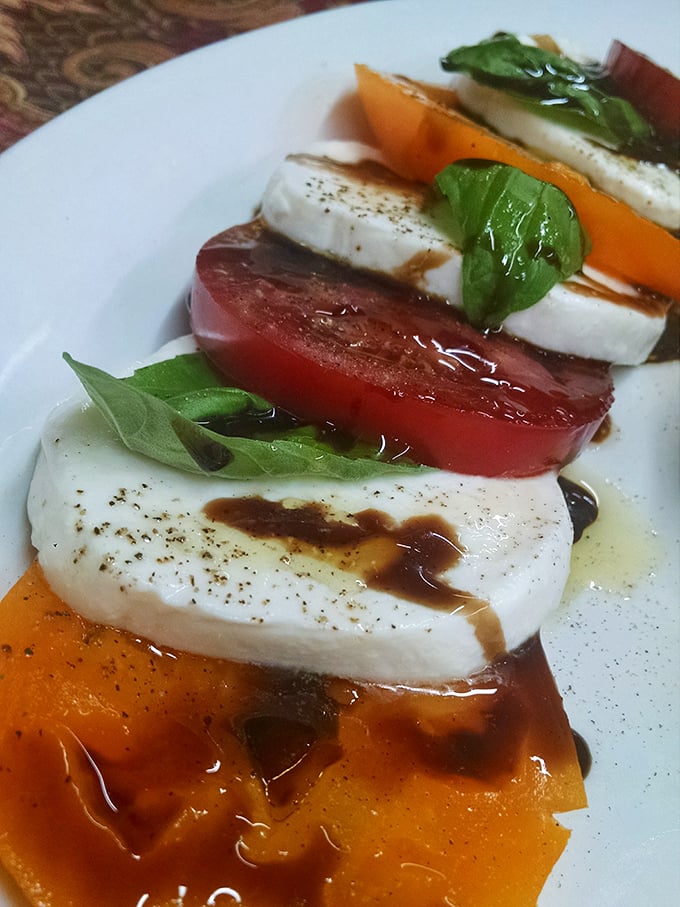 This isn't just a Caprese salad—it's summer on a plate, where tomatoes and mozzarella perform a perfectly choreographed dance drizzled with balsamic reduction.