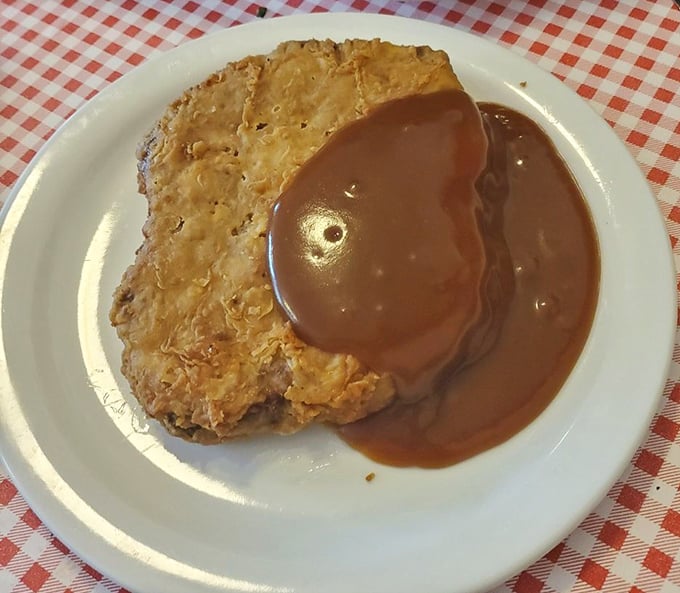 Country fried steak with gravy cascading over the edges like a delicious waterfall—proof that some lessons in indulgence are worth learning.