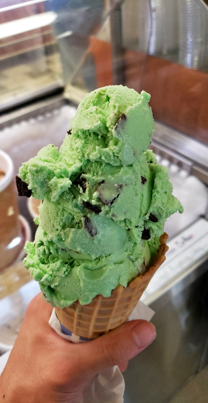 Mint chocolate chip stacked impossibly high on a waffle cone—not just dessert, but a structural marvel that demands to be photographed before devoured.