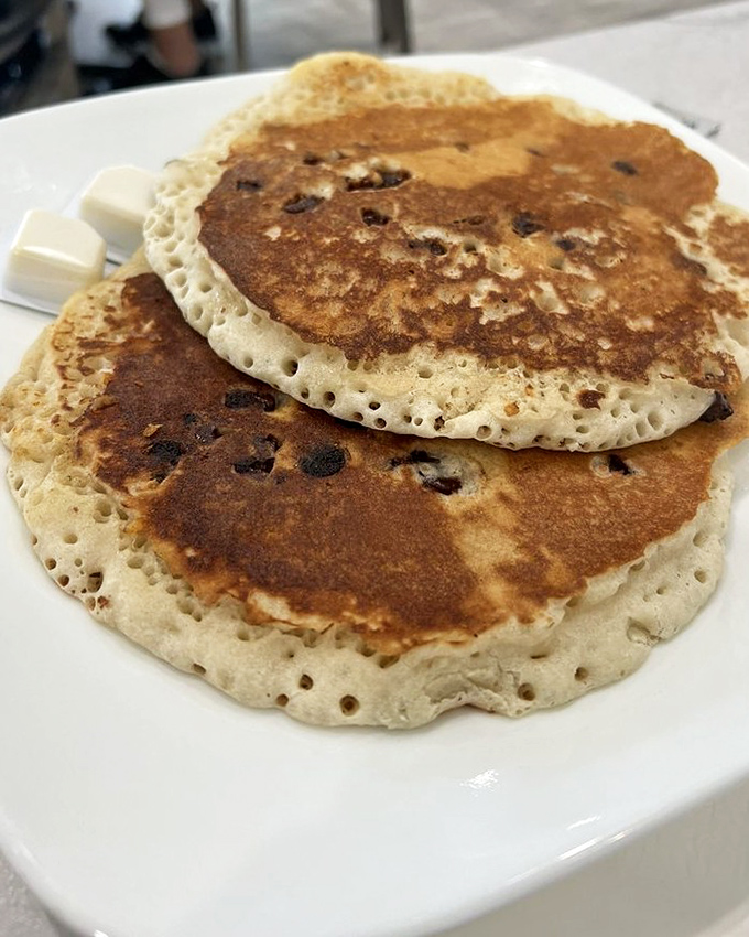 Chocolate chip pancakes with the perfect bubble structure—fluffy islands of breakfast joy that make mornings worth facing.