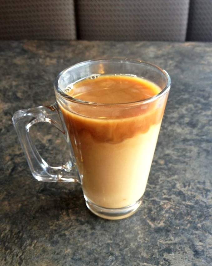Coffee served in a glass mug—because when it looks this good, you deserve to watch the cream create mesmerizing swirls as it joins the party.