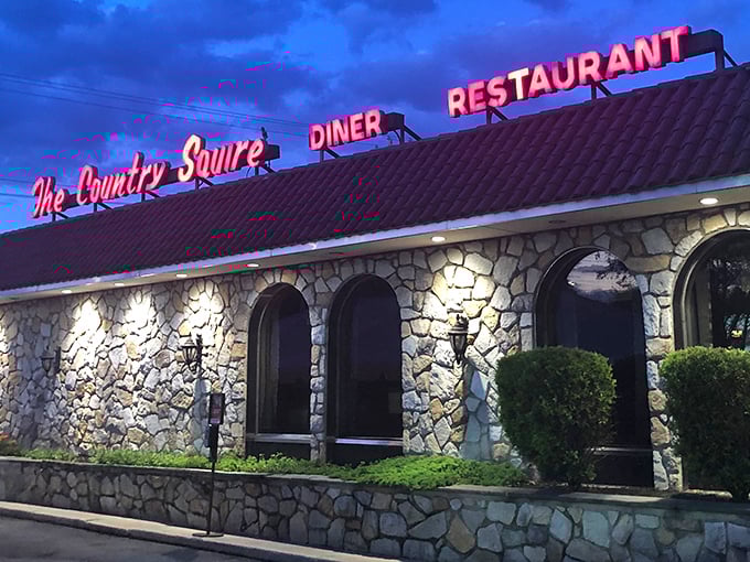 As evening falls, the Country Squire's neon glow transforms from mere signage to a beacon of culinary comfort against the twilight sky—a promise of warmth inside.