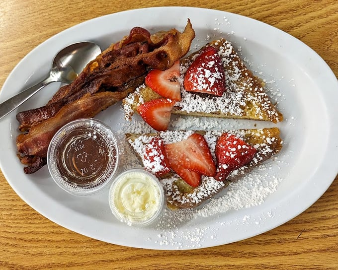 French toast dusted with powdered sugar, fresh strawberries, and bacon on the side. The sweet-savory combination that makes mornings worth facing.