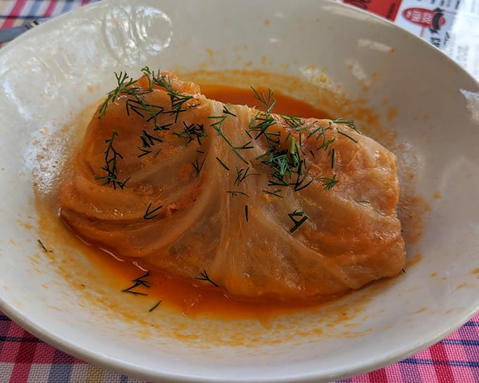 A cabbage roll lounging in tomato sauce like it's at a spa. The fresh dill sprinkled on top isn't garnish—it's the perfect finishing touch to this Eastern European classic.