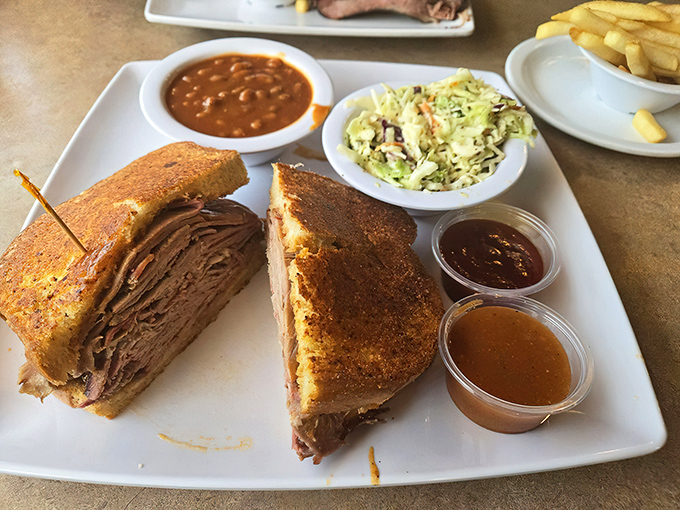 This isn't just a sandwich—it's architecture. Layers of perfectly smoked meat with coleslaw, beans, and sauce cups standing by for customized flavor adventures.