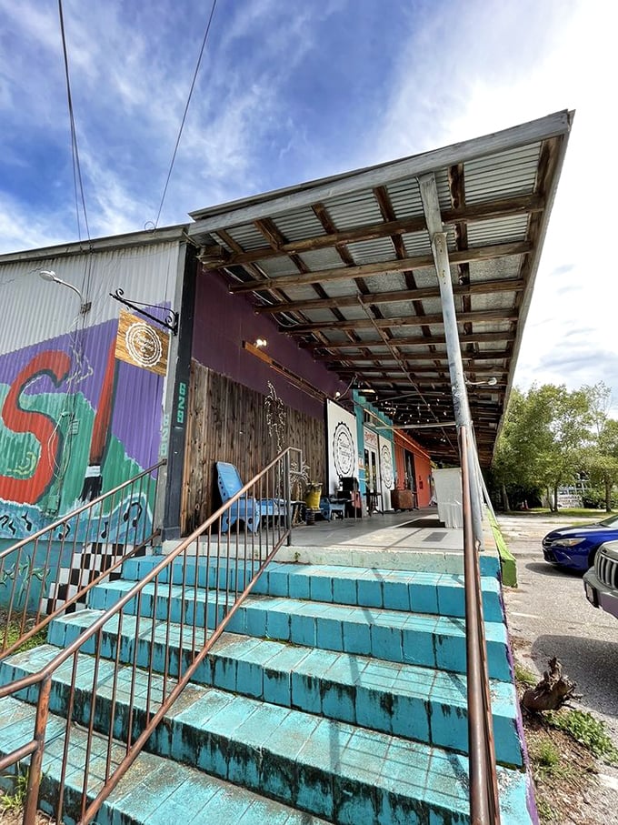 Approaching the multi-colored exterior feels like discovering a secret clubhouse for treasure hunters—complete with turquoise steps and rustic charm.