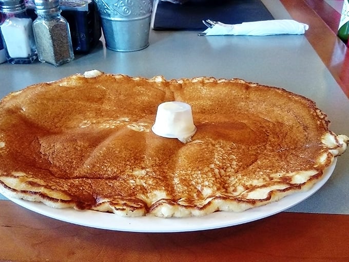 A pancake so perfectly golden and massive it deserves its own zip code – butter melting into a delicious puddle on top.