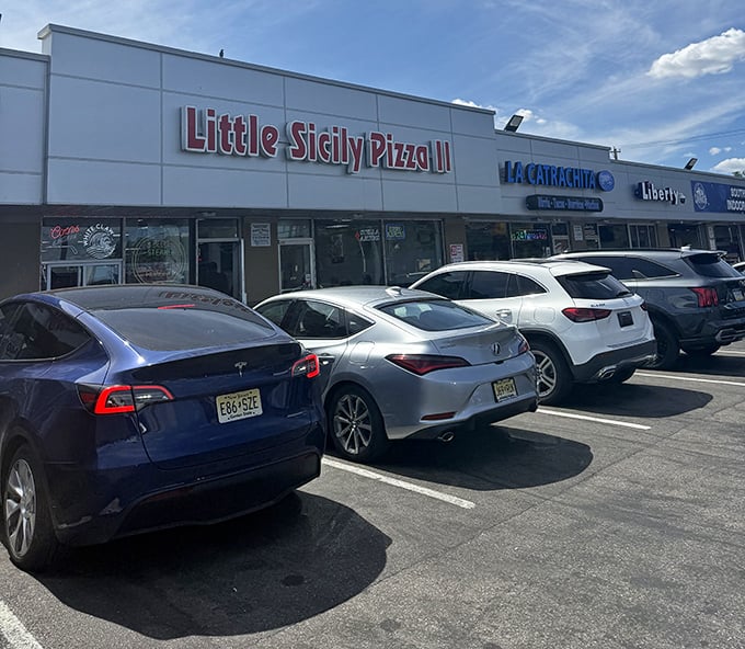 Even in daylight, Little Sicily Pizza II commands attention in its strip mall home, with a packed parking lot that tells the real story.