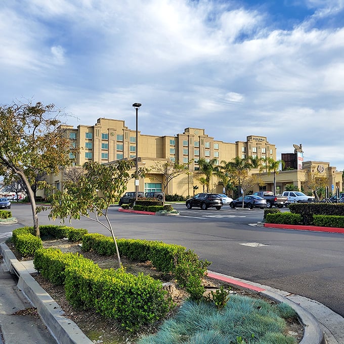 Manicured landscaping frames the parking area, where cars wait patiently while their owners engage in the ancient sport of outlet shopping.