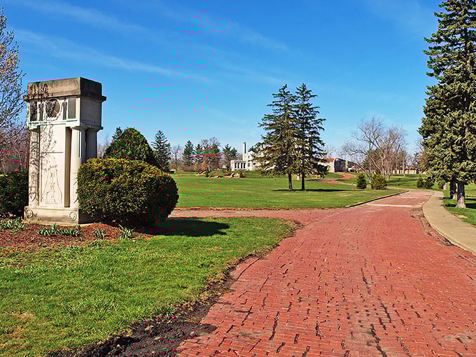 A stone monument stands sentinel along the brick pathway, guiding visitors toward a castle experience that feels delightfully out of place in Ohio.