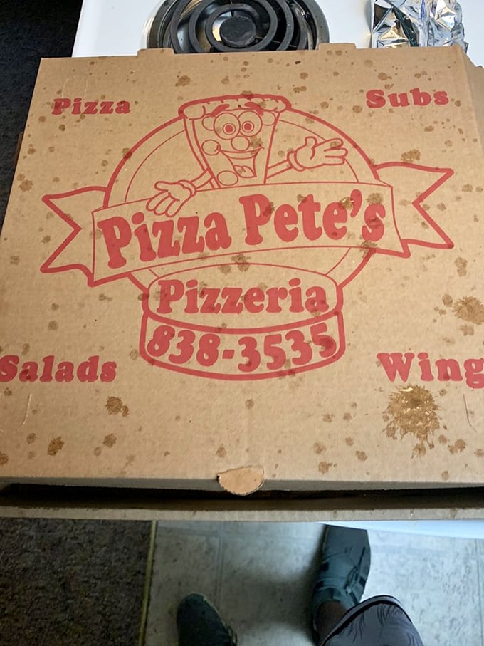 The pizza box – humble vessel of happiness, stained with the evidence of quality ingredients. That cartoon mascot knows he's delivering joy.