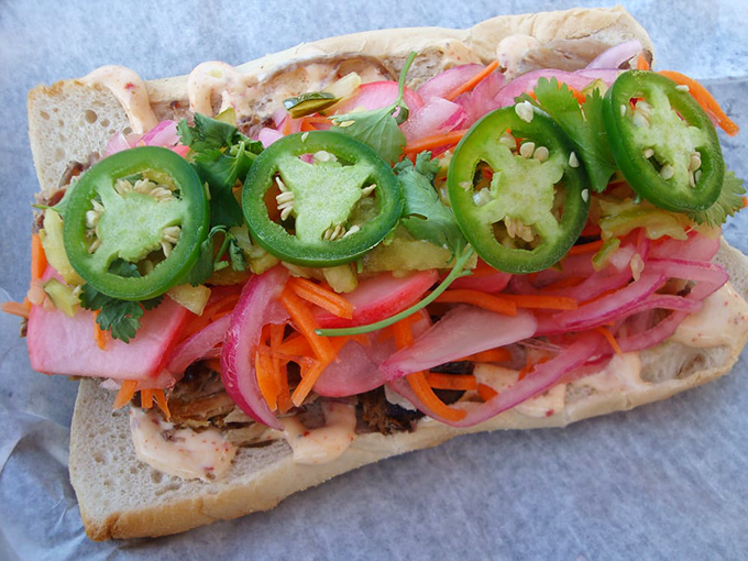 A sandwich that's practically a garden on bread—where pickled vegetables and jalapeños bring bright crunch to balance the smoky meat beneath.