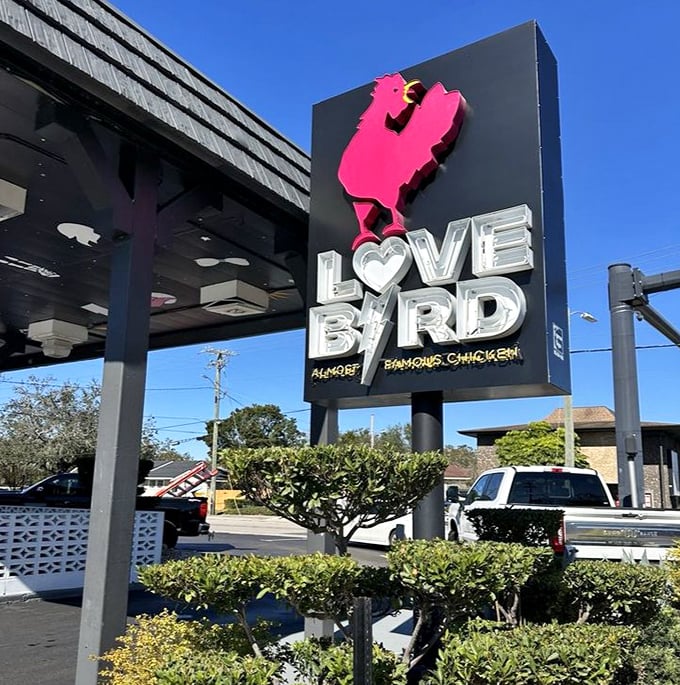 The pink chicken silhouette on the LoveBird sign stands proud against the blue Florida sky – a monument to poultry perfection in Lakeland.