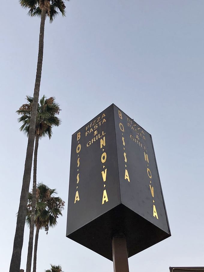 The towering sign stands like a beacon for hungry travelers—a vertical promise of Brazilian delights waiting just below.