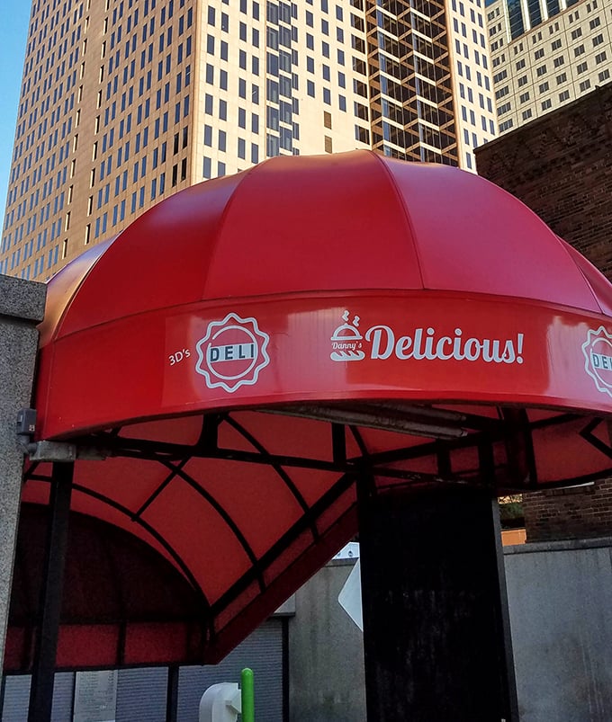 Downtown high-rises provide a dramatic backdrop for that signature red awning—a splash of color and promise in the urban landscape.
