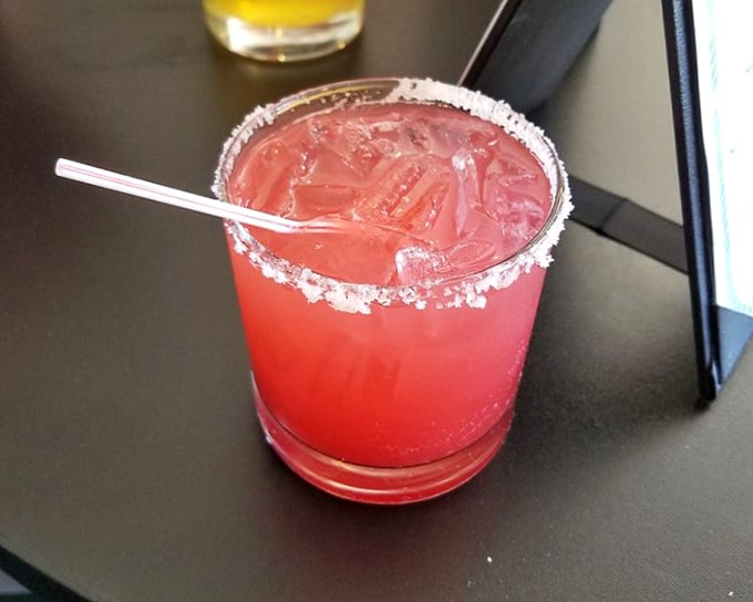 A vibrant strawberry margarita with salt-kissed rim – because sometimes the perfect seafood dinner deserves a sunset in a glass.