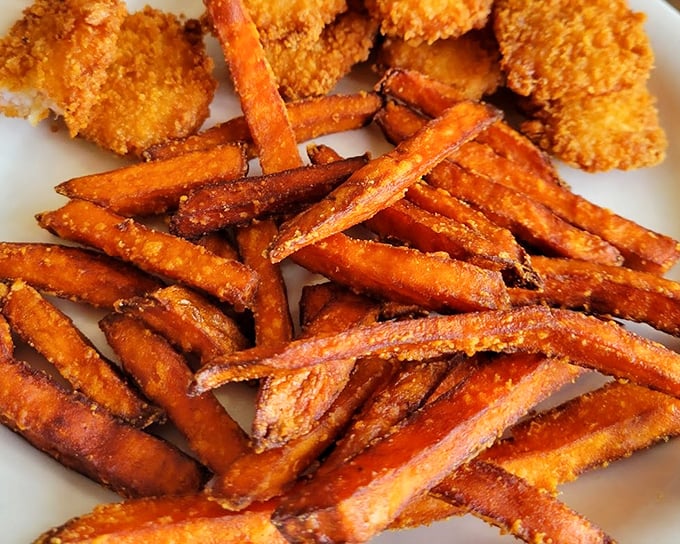 Sweet potato fries with the perfect crisp-to-soft ratio, alongside what appears to be chicken—the dynamic duo of comfort food superheroes.