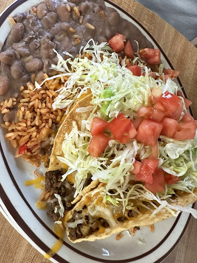 This isn't just a taco plate – it's a colorful celebration of New Mexican flavors with beans, rice, lettuce, and fresh tomatoes.