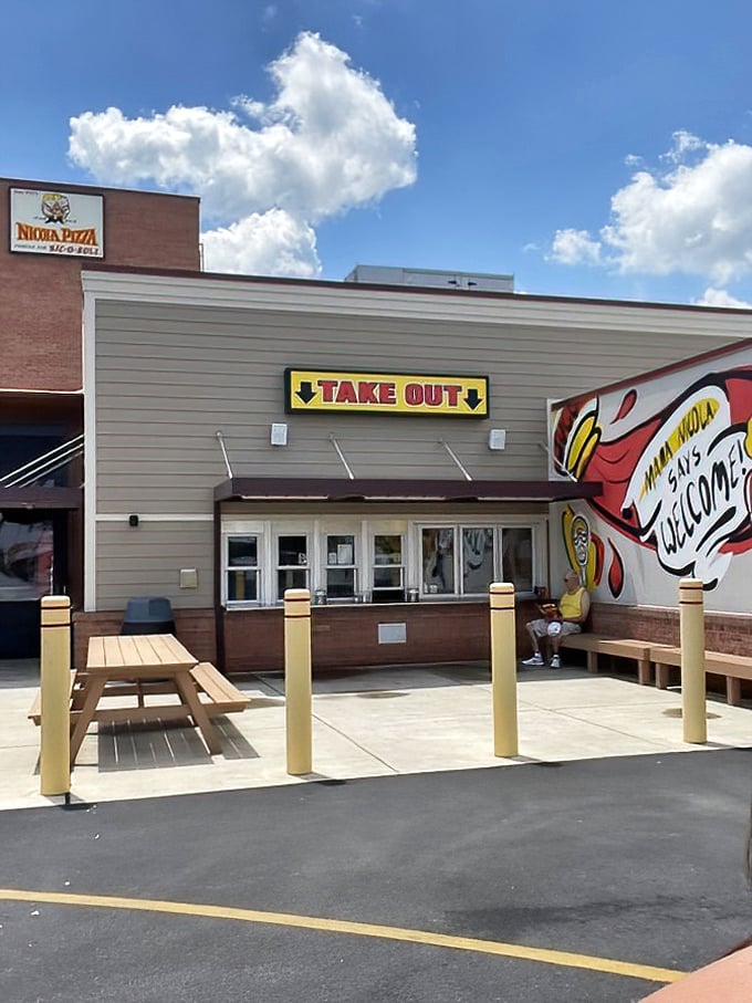 The takeout window where dreams come true – just follow the "WELCOME" sign to pizza paradise.