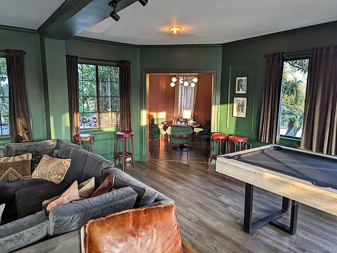 This game room's rich green walls and shuffleboard table create the perfect space for friendly competition—medieval knights probably settled disputes similarly, minus the cocktails.