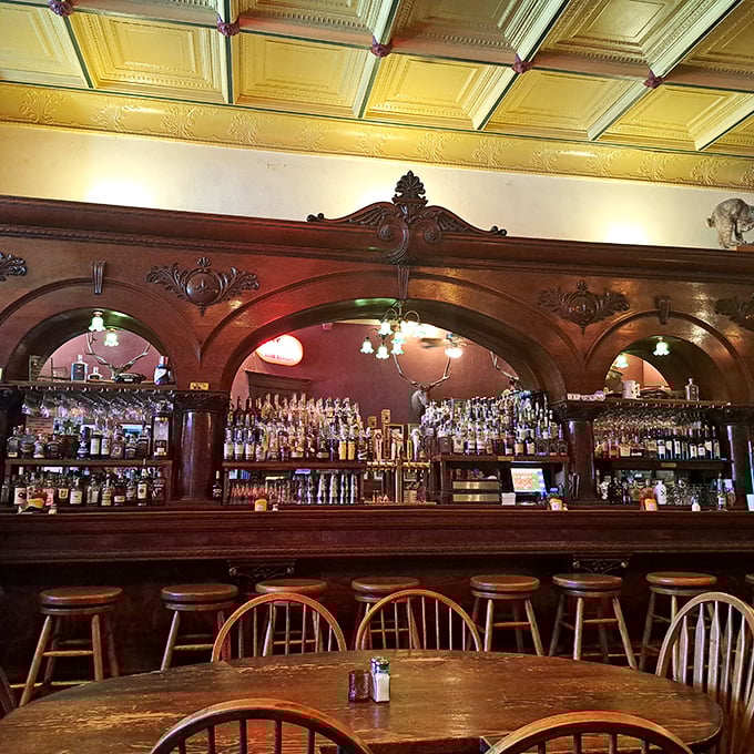 The bar where legends were born and whiskey flowed—ornate woodwork frames bottles that promise stories with every pour.