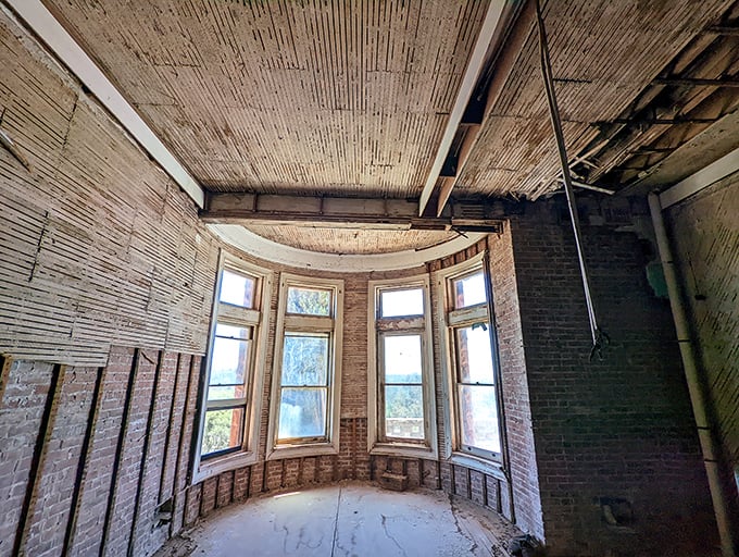 Sunlight streams through bay windows in a forgotten corner. Nature slowly reclaiming what humans built with such grand ambition.
